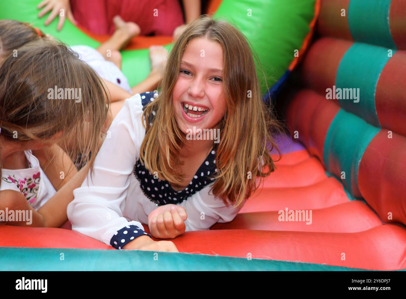 Cute girl in a colorful inflatable bounce house. having fun at a ...