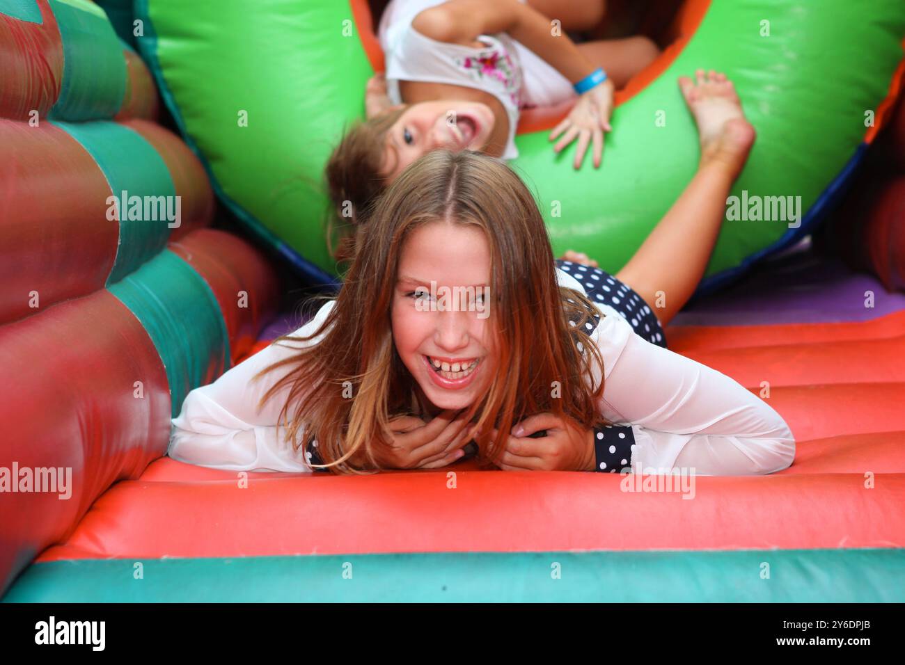 Cute girl in a colorful inflatable bounce house. having fun at a ...