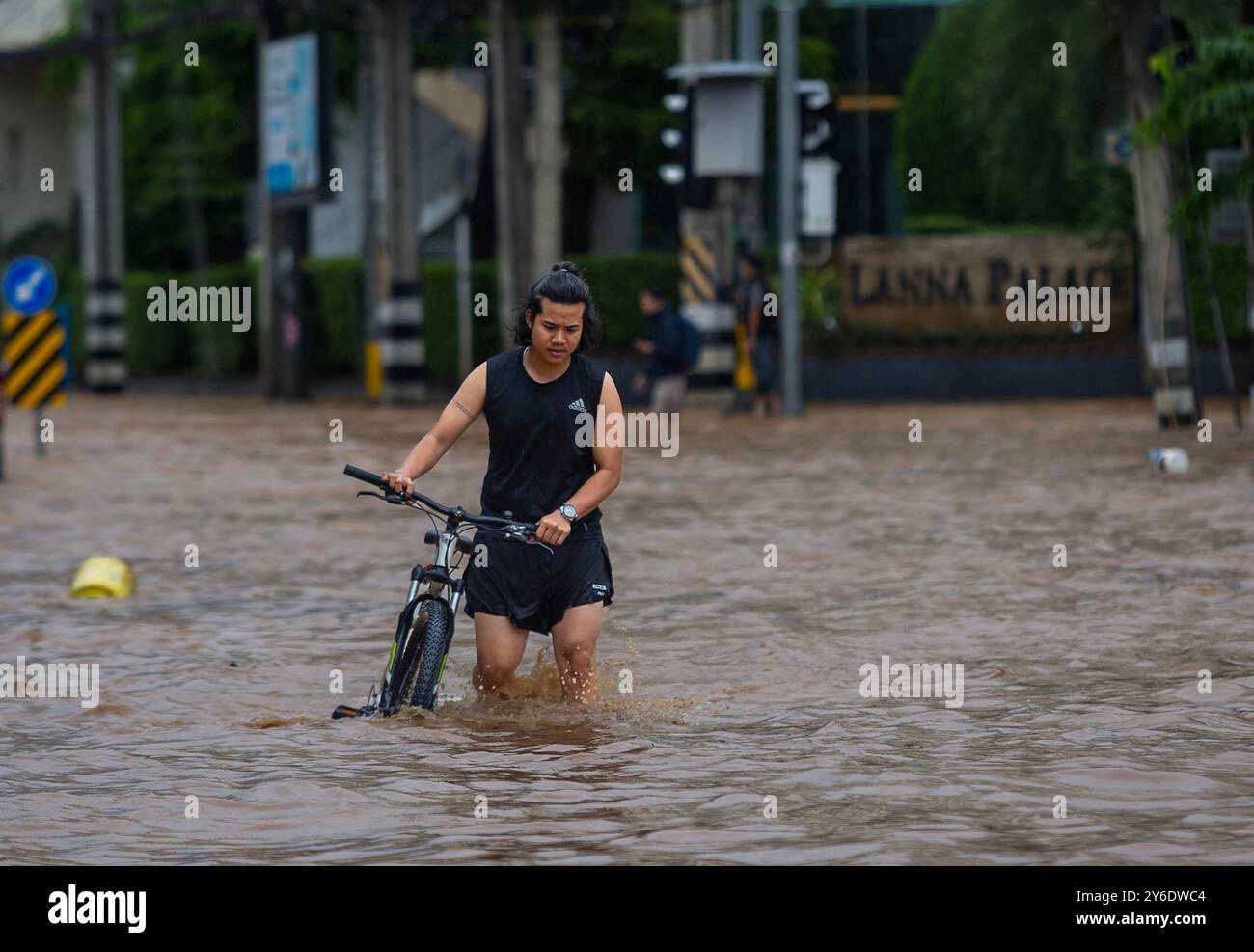 A man with a bicycle walks along a flooded street in the Chang Khlan ...