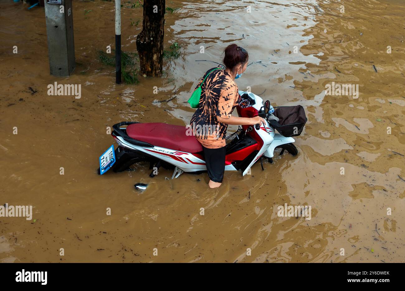 A woman seen riding a motorcycle along a flooded street in the Chang ...