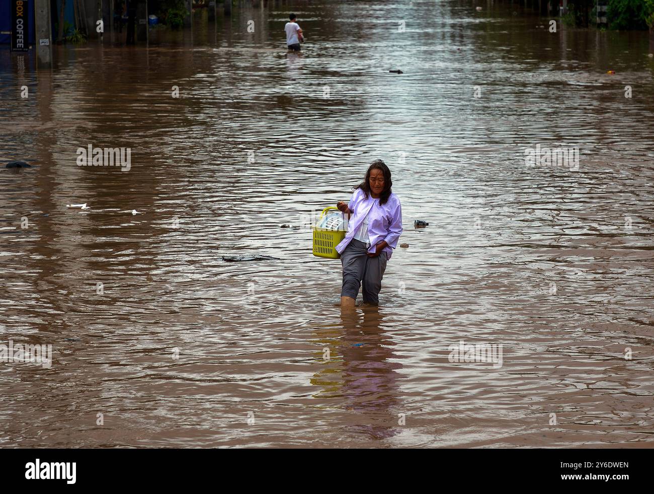 A woman walks along a flooded street in the Chang Khlan area due to the ...