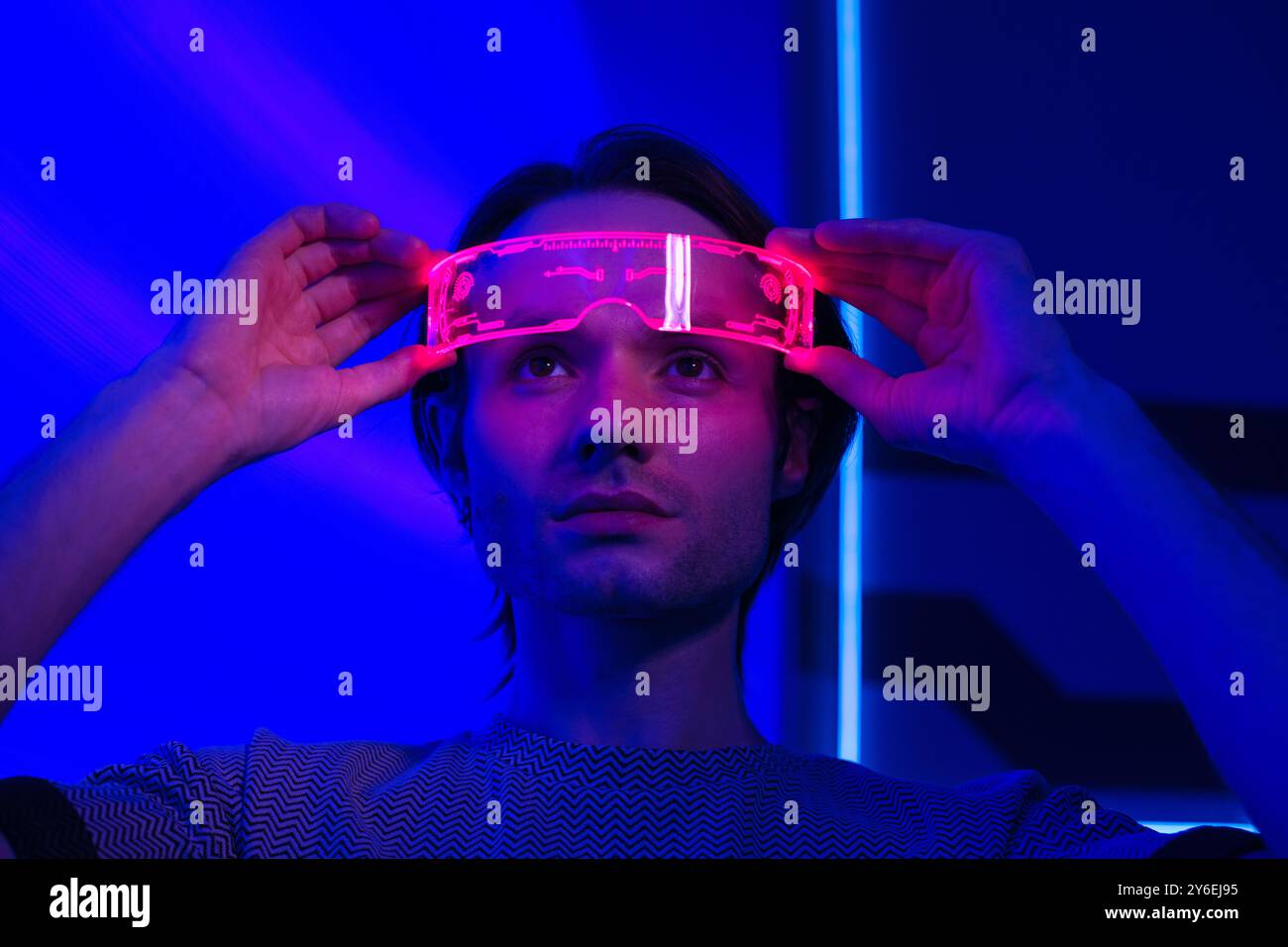 Creative futuristic man with smart neon glasses in a neon room a neon blue wall background ...