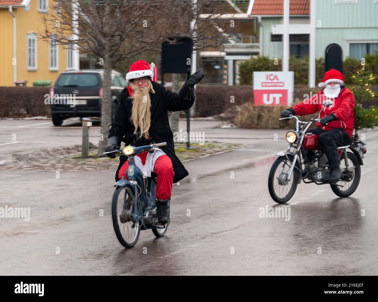 In a charming winter setting, two people dressed as Santa Claus ride ...