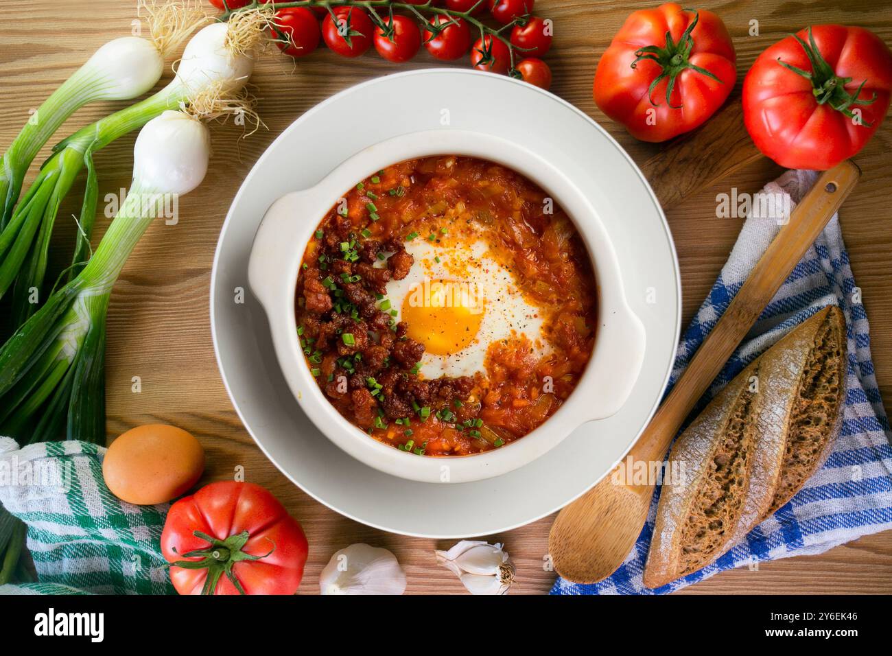 Spanish tapa of baked egg with chorizo and tomato. Top view table with ...