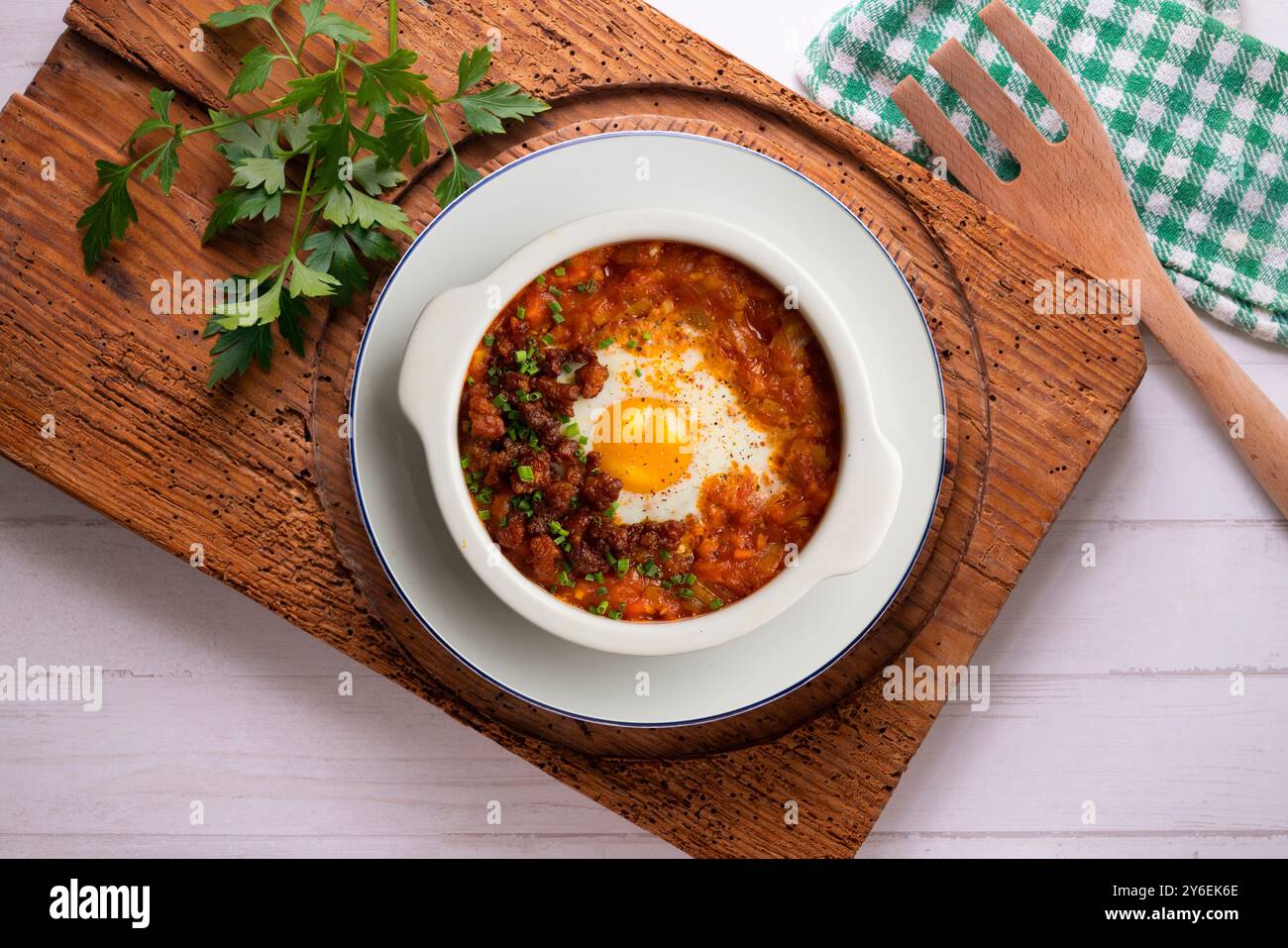 Spanish tapa of baked egg with chorizo and tomato. Top view table with ...