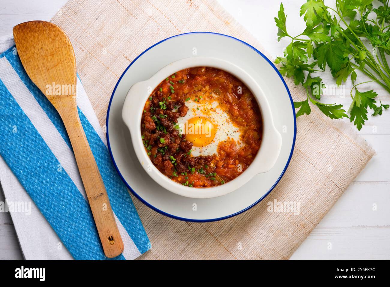 Spanish tapa of baked egg with chorizo and tomato. Top view table with ...