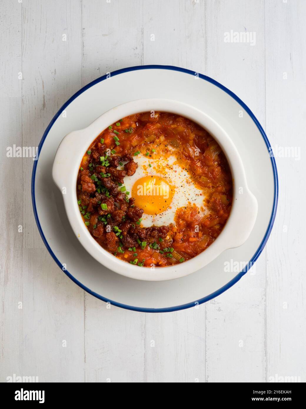 Spanish tapa of baked egg with chorizo and tomato. Top view table with ...