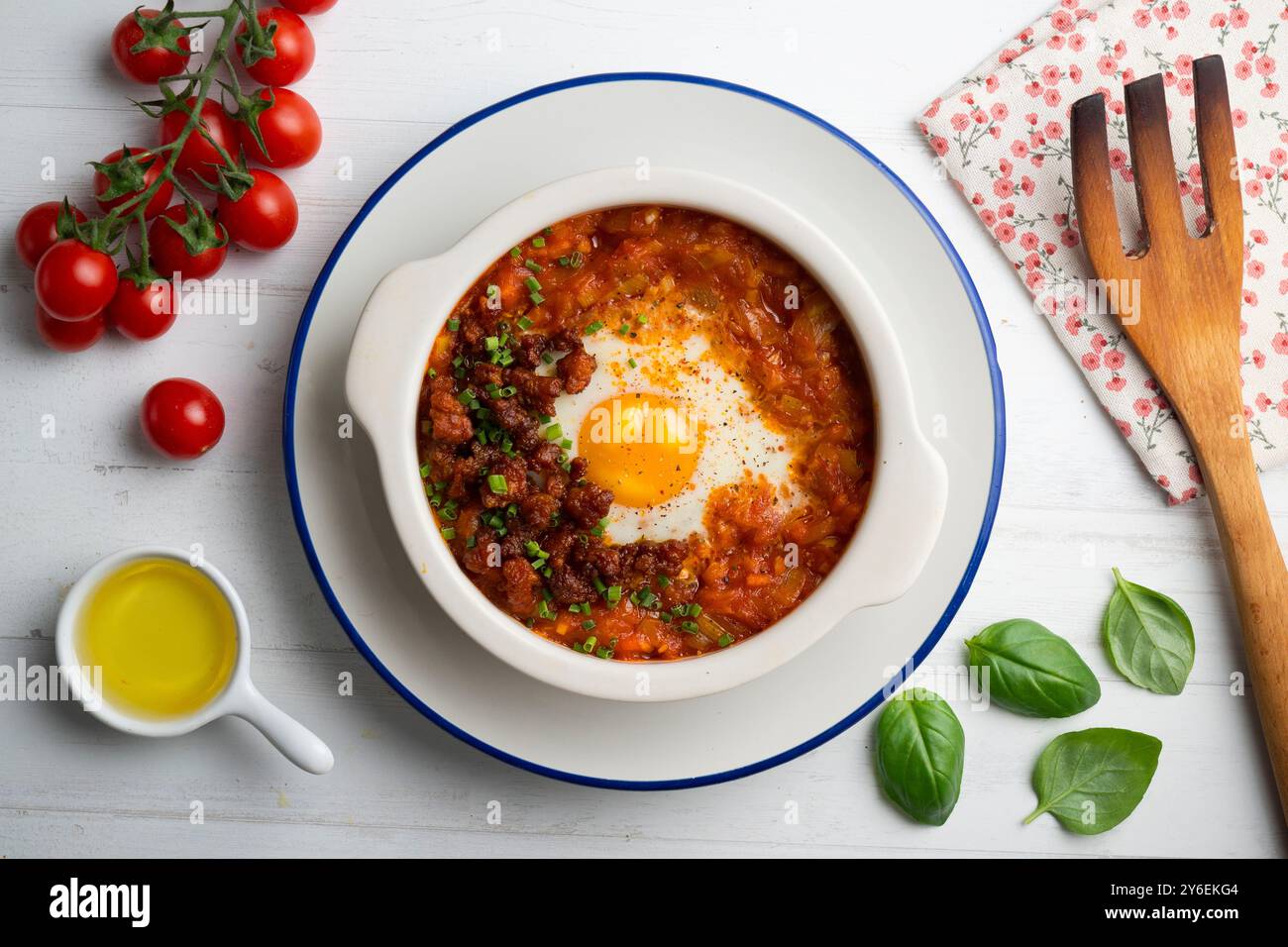 Spanish tapa of baked egg with chorizo and tomato. Top view table with ...