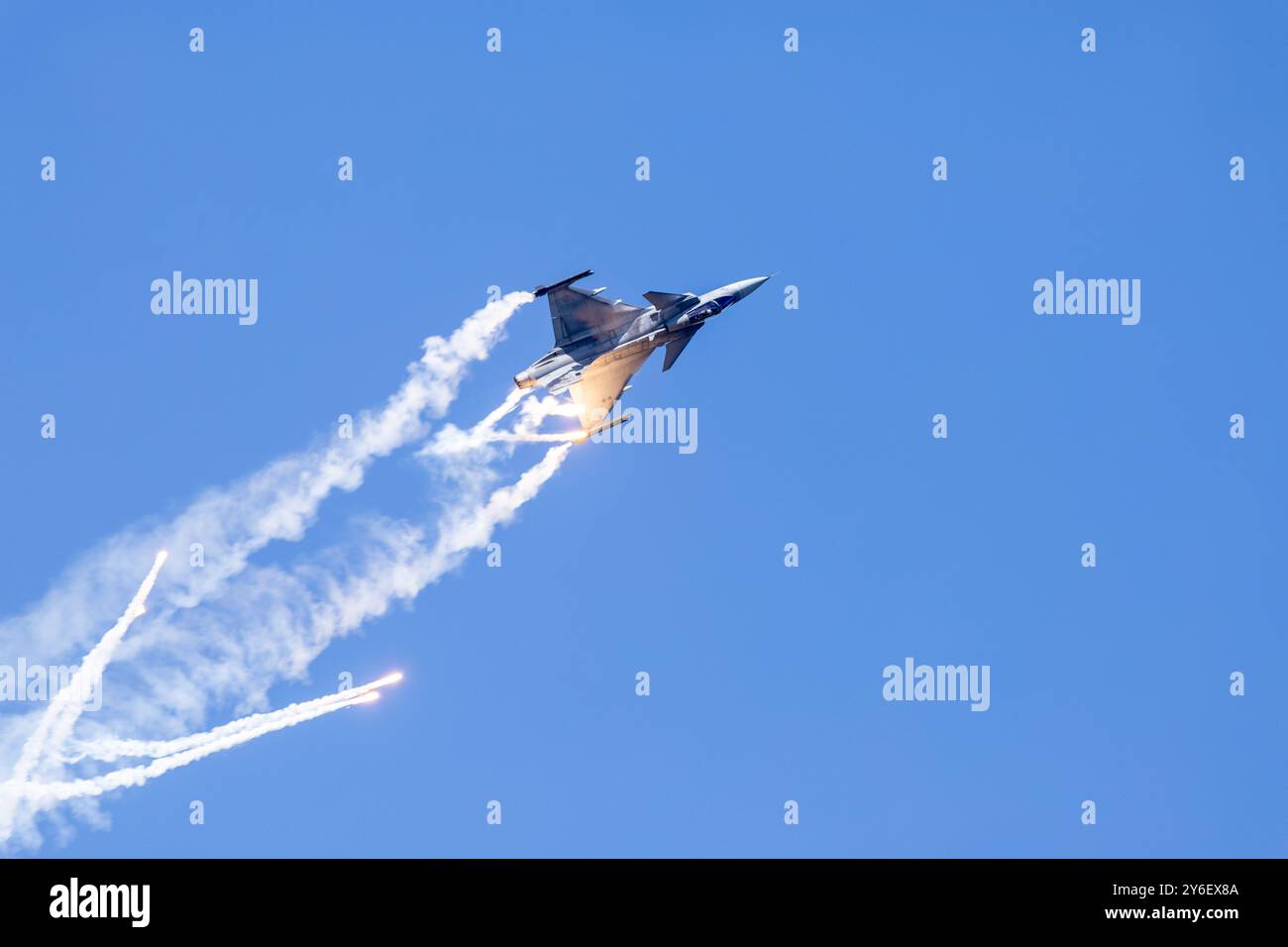 A fighter jet performing an aerial maneuver with smoke trails against a ...