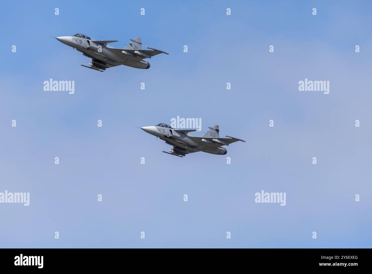Two military fighter jets flying in formation against a clear blue sky ...