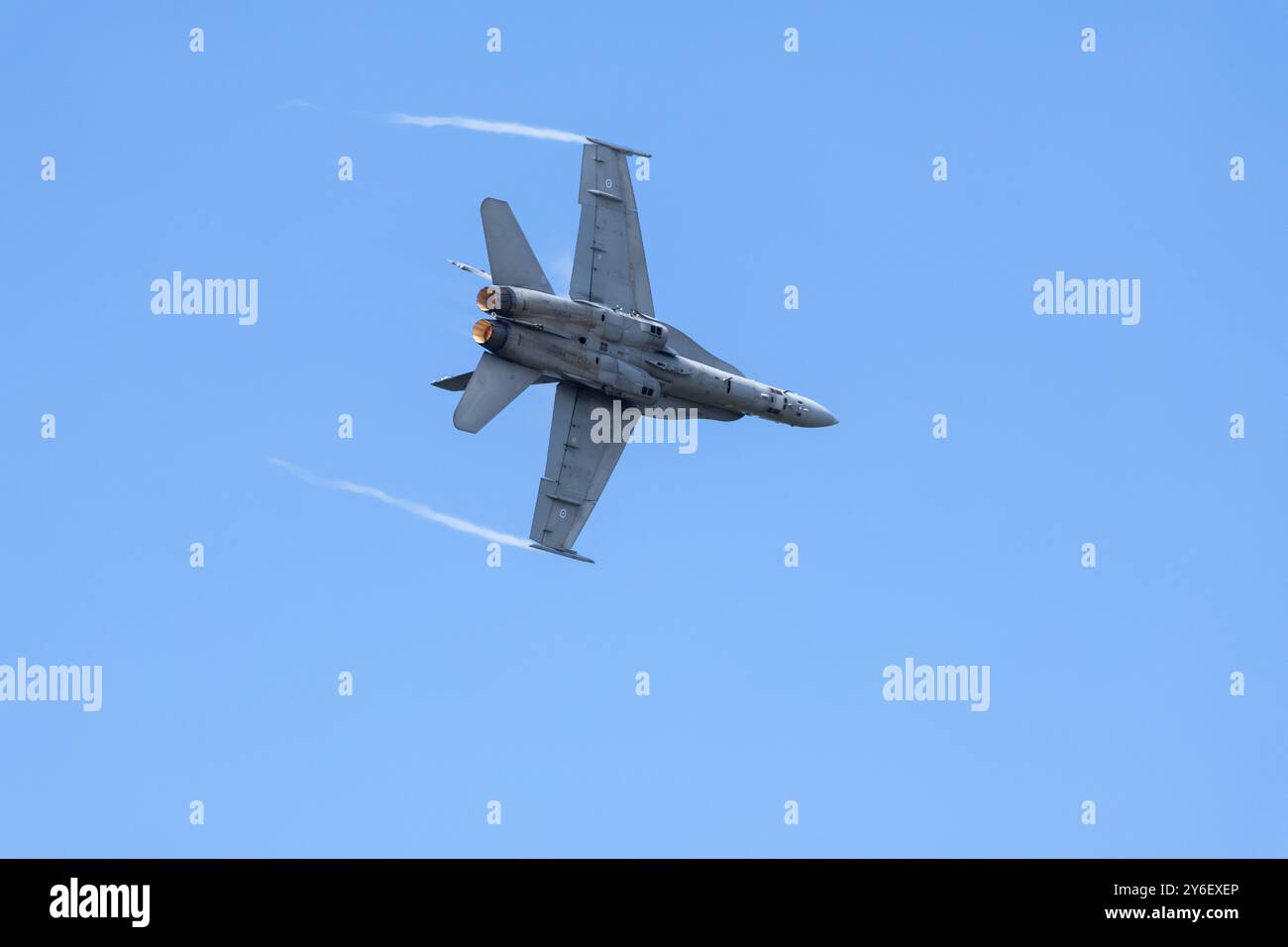 A military jet aircraft performing an aerial maneuver against a clear ...
