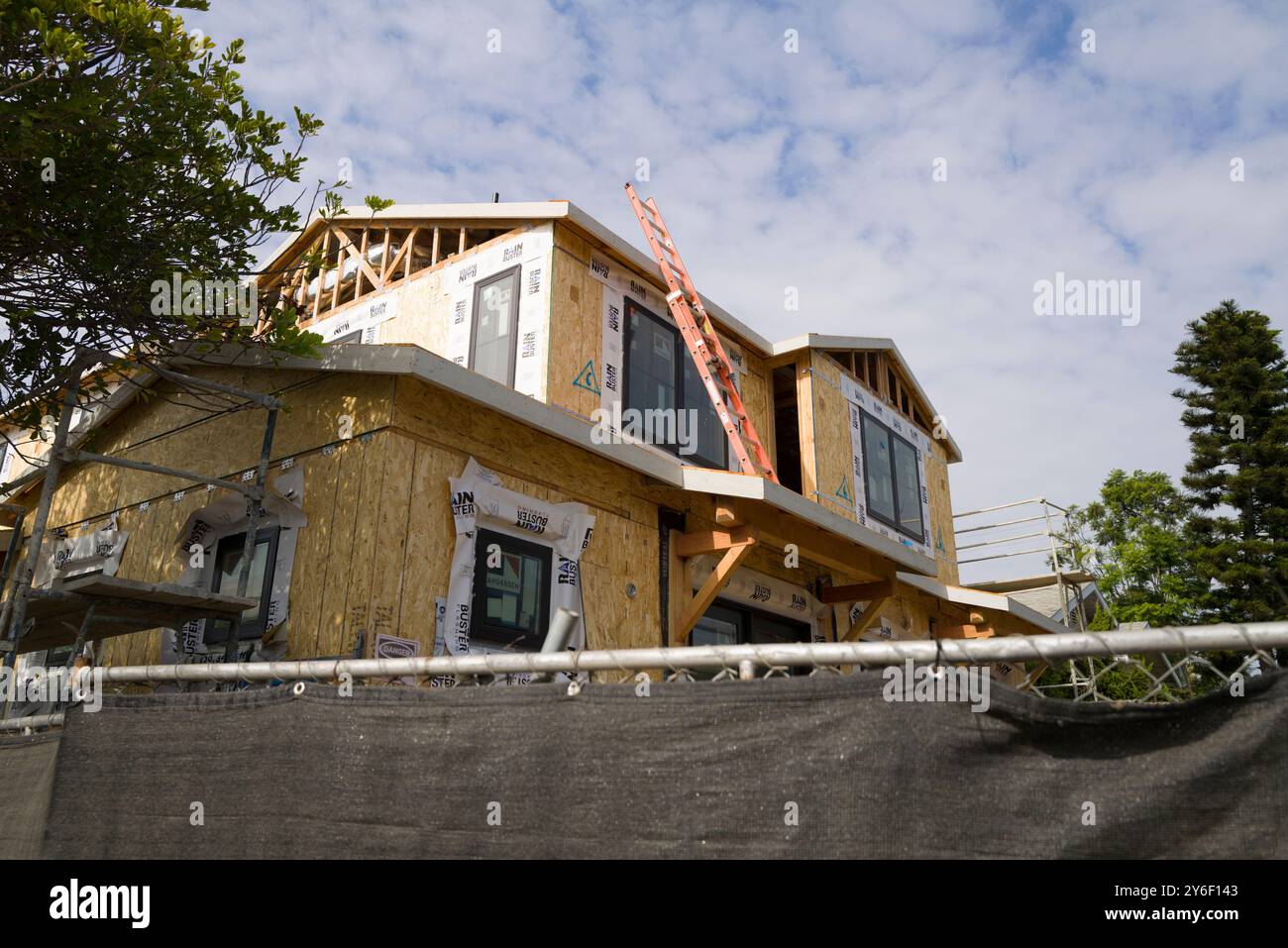 New homes under construction with scaffolding and plywood walls ...