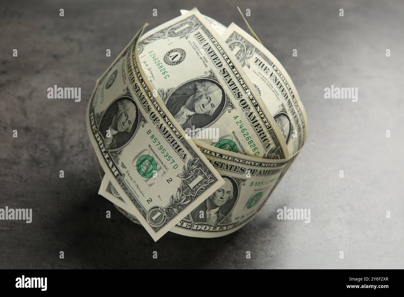 Ball made of dollars on grey table, closeup Stock Photo - Alamy
