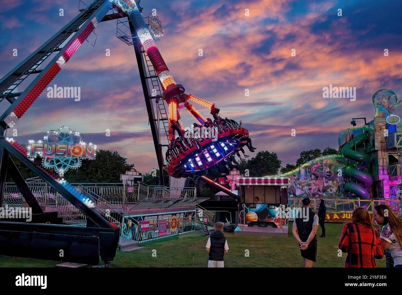 Electrifying funfair ride illuminating the twilight sky, creating a ...
