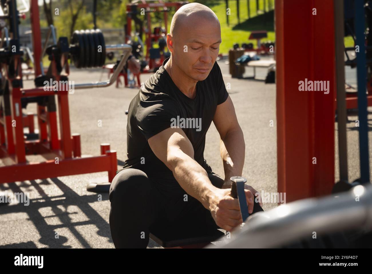 Lat rowing exercises. Adult man training at public gym park. Outdoors ...