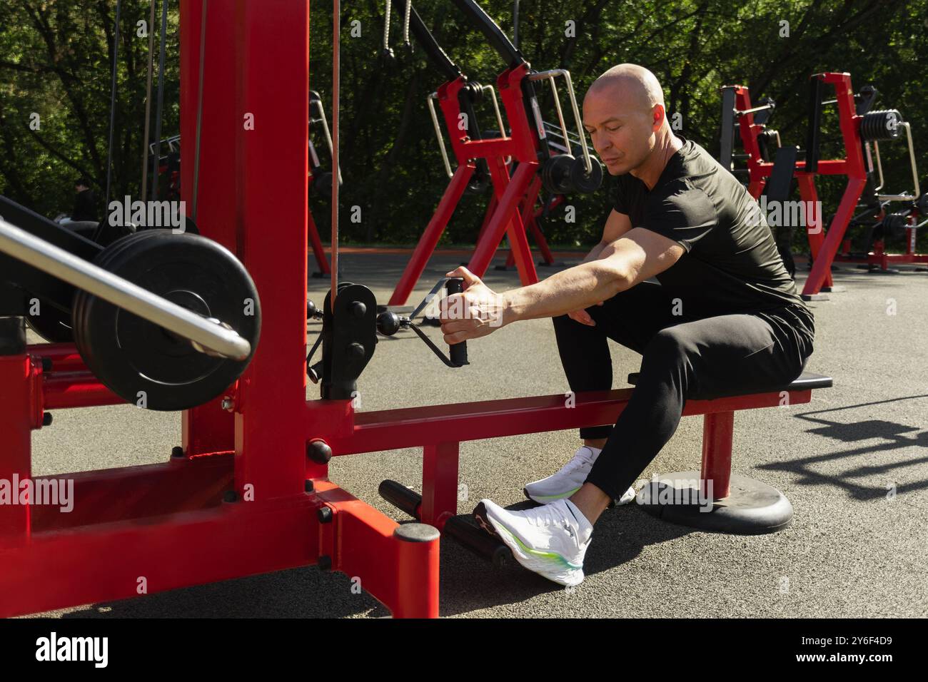 Lat rowing exercises. Adult man training at public gym park. Outdoors ...