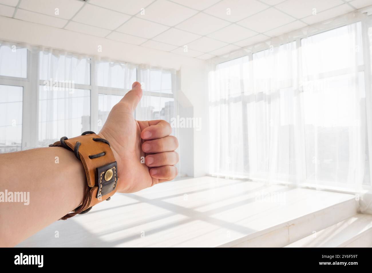 Male hand with brown leather bracelet showing thumbs up sign against ...