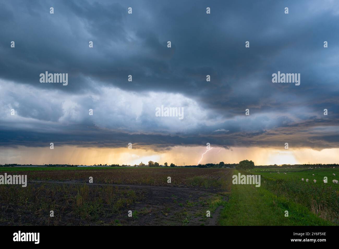 Lightning bolt is hitting the earth from a dark storm cloud during ...