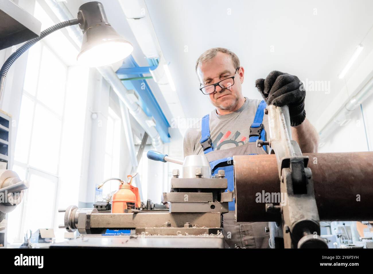 A technician operates a lathe machine in an industrial workspace ...
