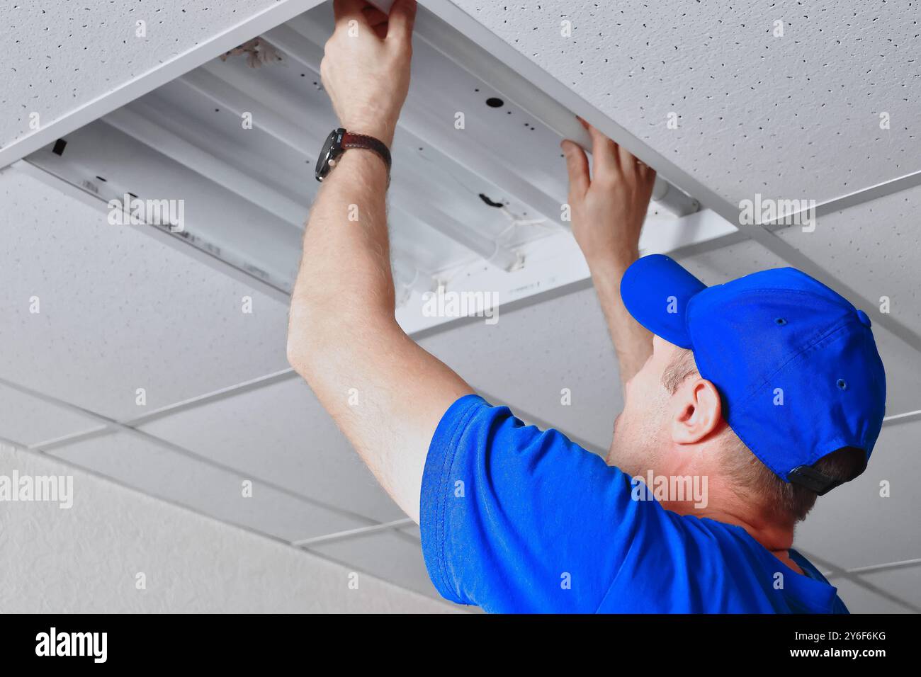 A maintenance worker in a blue cap and blue clothing is working on a ...
