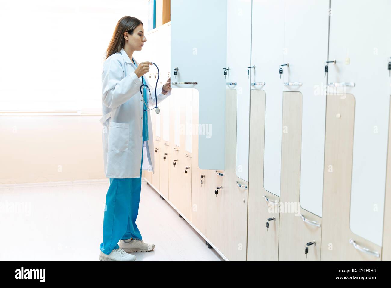 Young female doctor in a changing room putting his clothes to the ...
