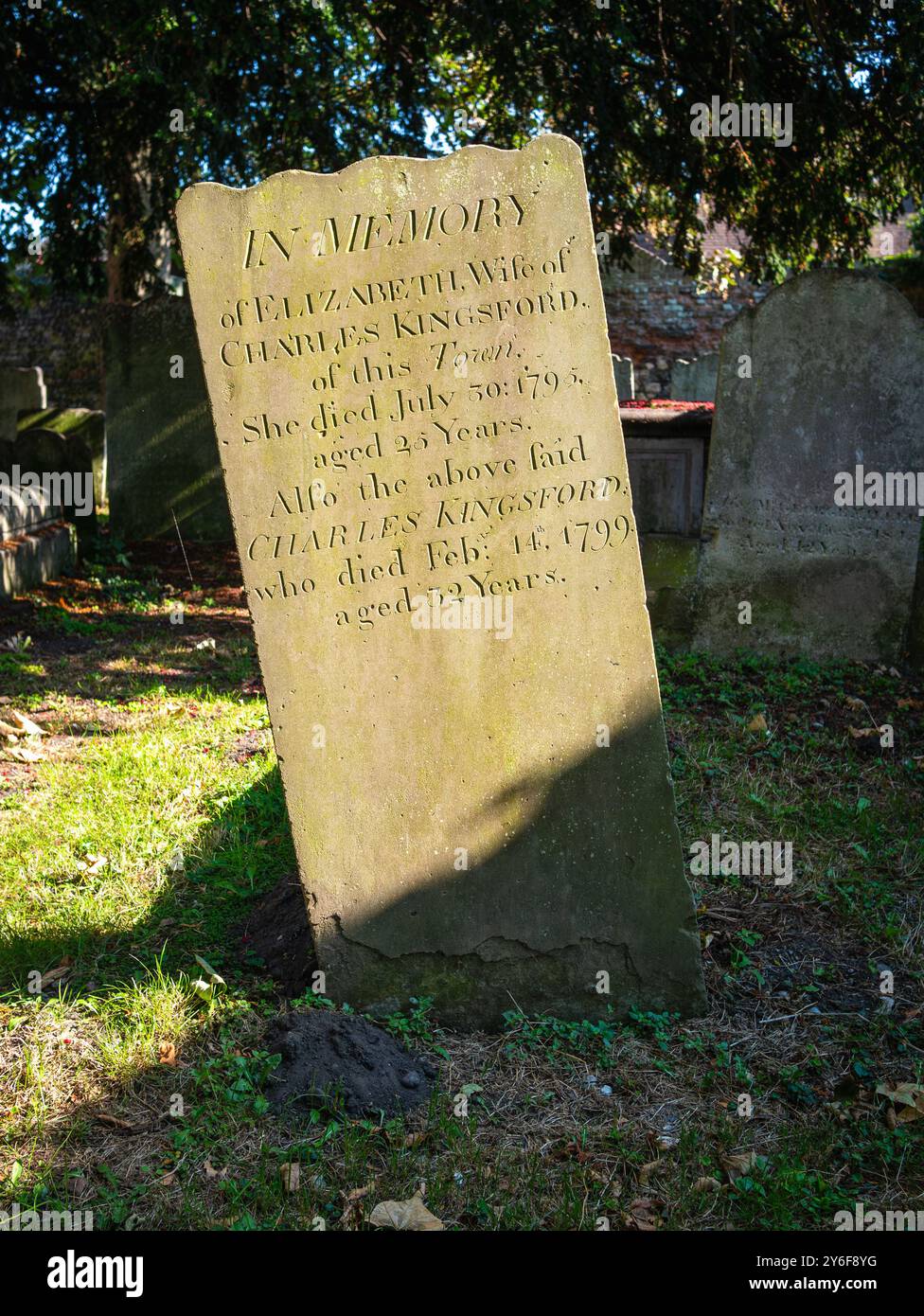 A crooked gravestone bathed in heavy side lighting, casting deep ...