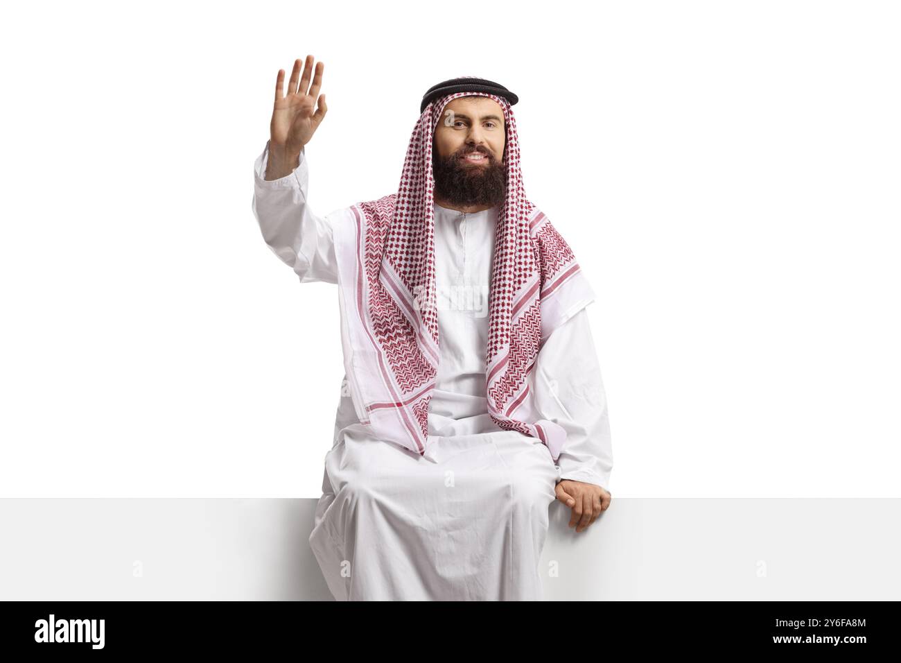 Saudi arab man sitting on a blank panel and waving isolated on white ...
