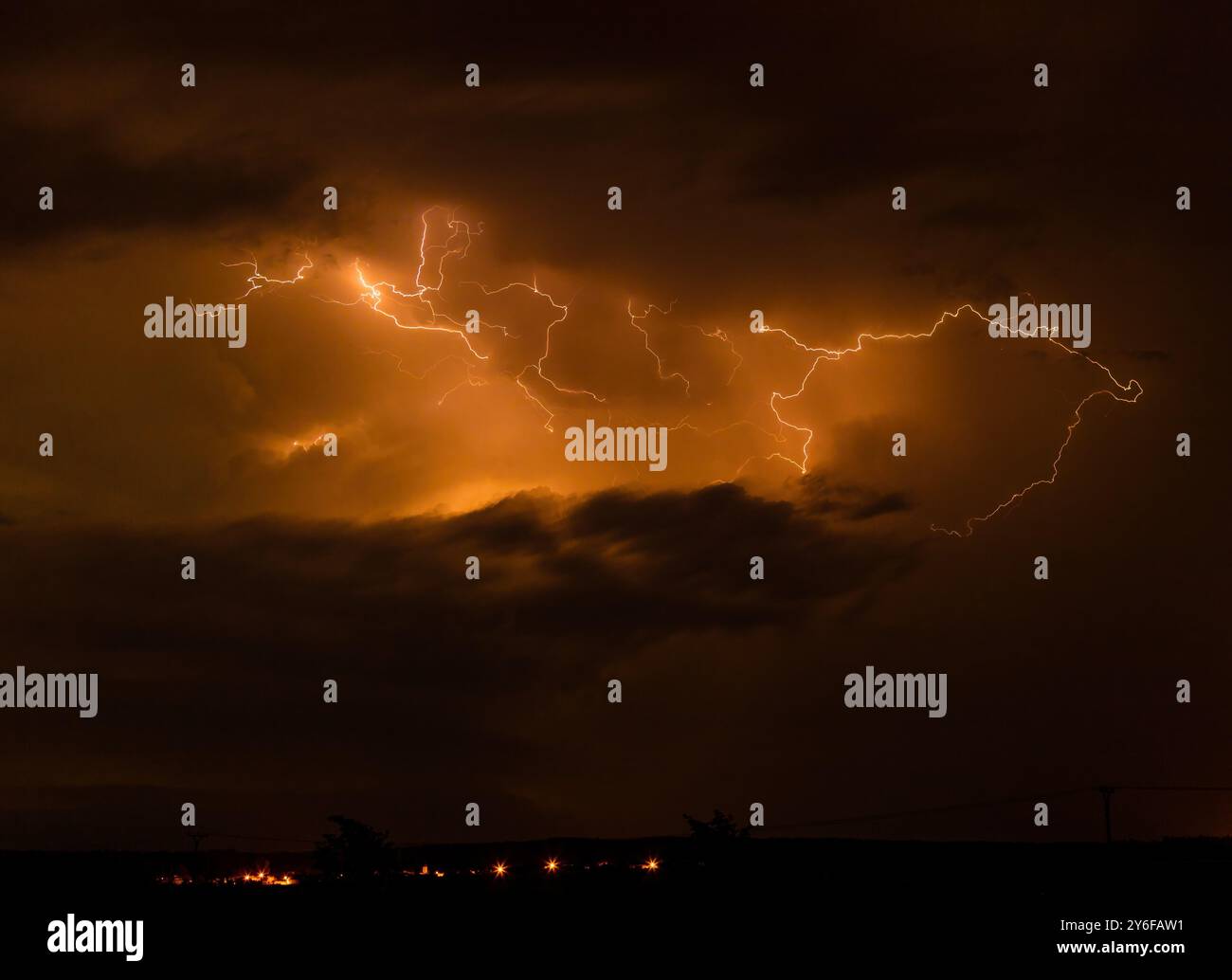 A dramatic night sky illuminated by lightning with dark clouds and a ...