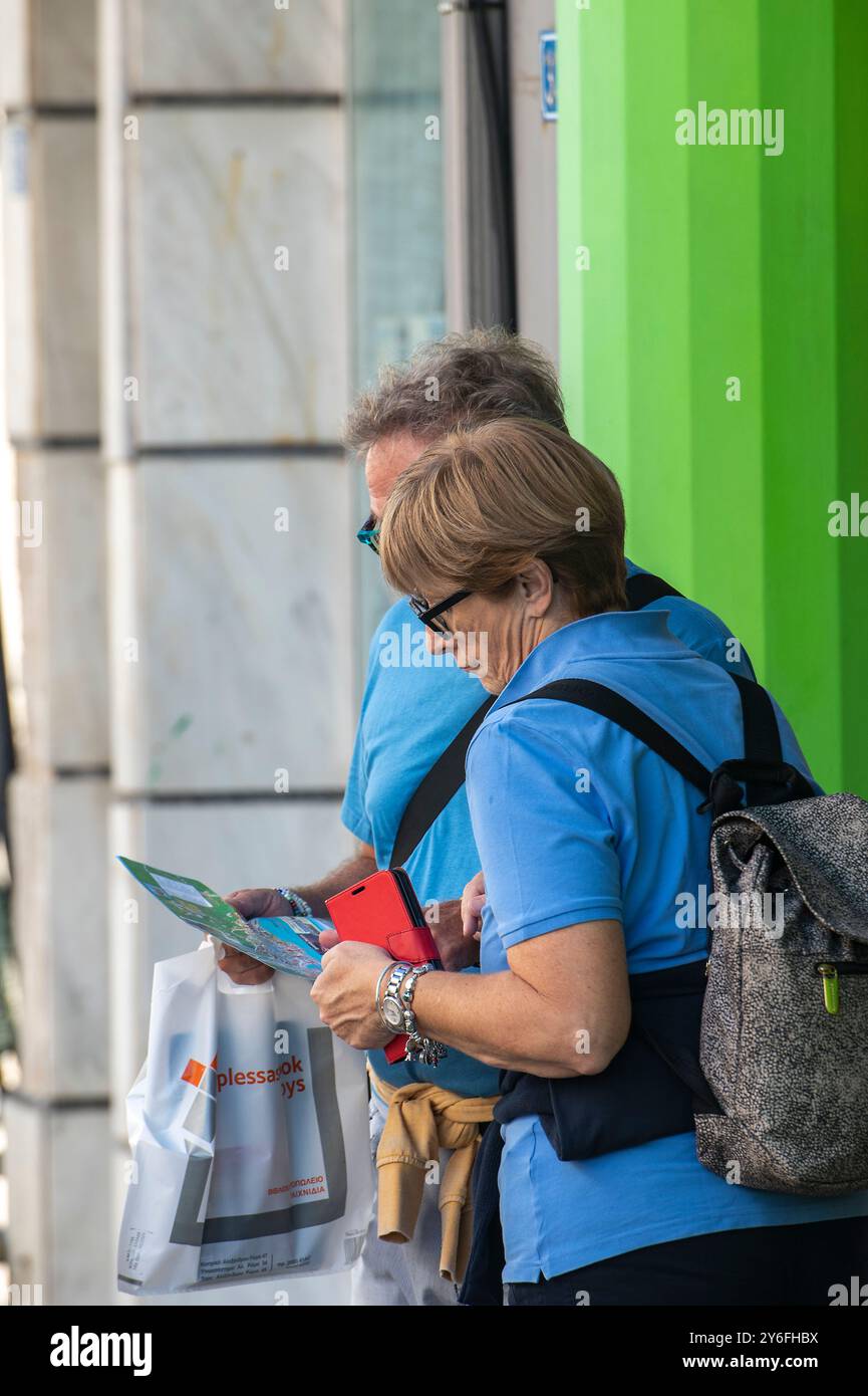 middle-aged tourist couple using a street map to find their way around ...