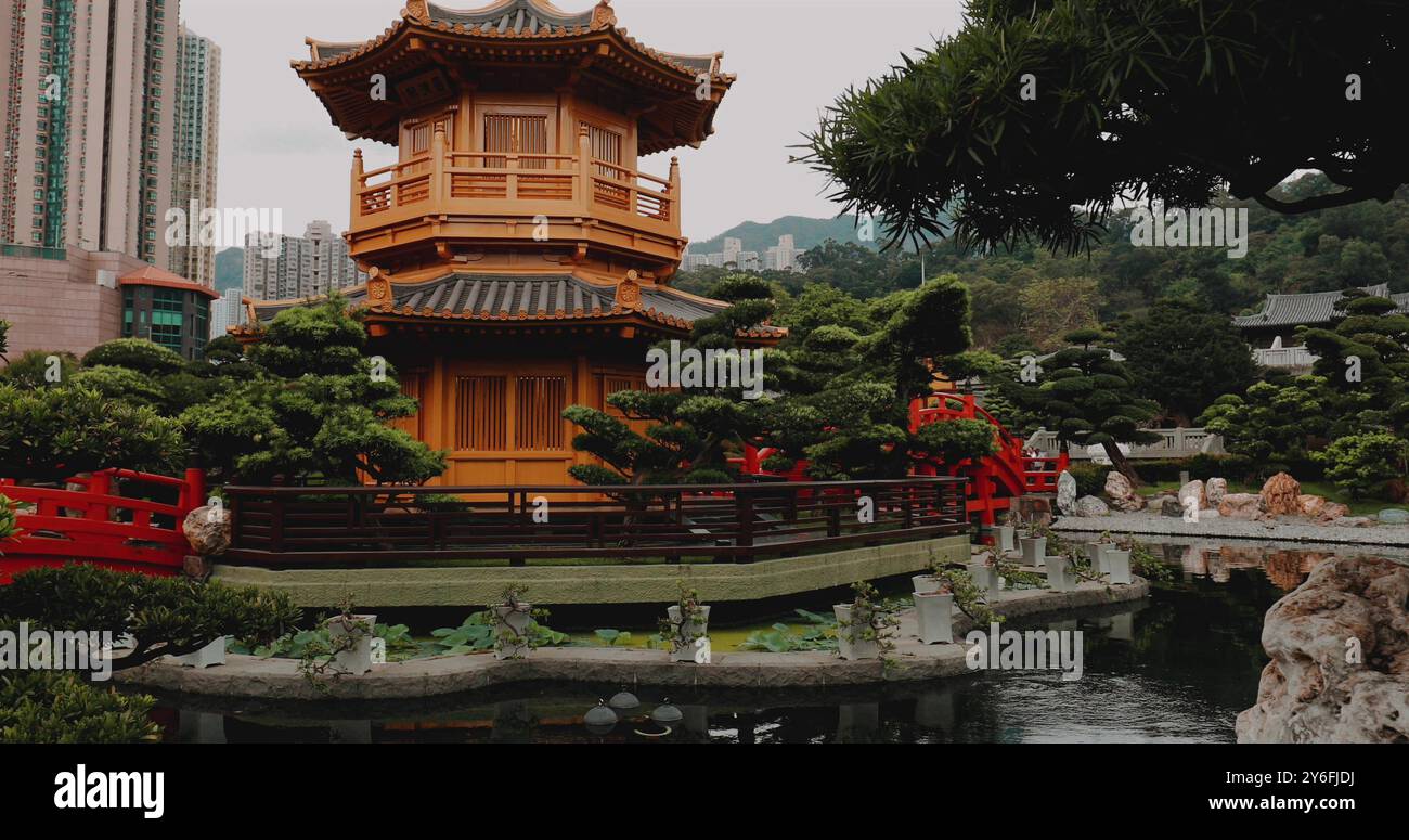 Traditional Chinese garden with pavilion, red bridge, lush greenery ...