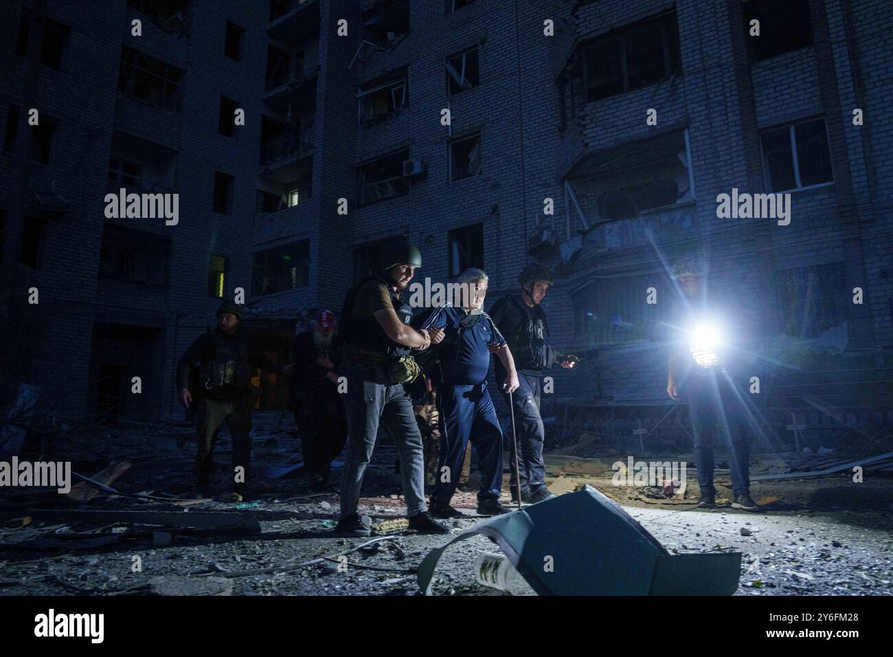 Police officers evacuate a man from a residential building heavily ...