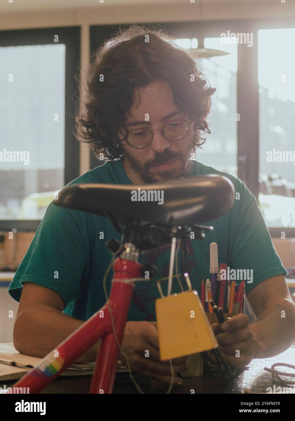 Young bike mechanic is carefully repairing a vintage bicycle in his ...