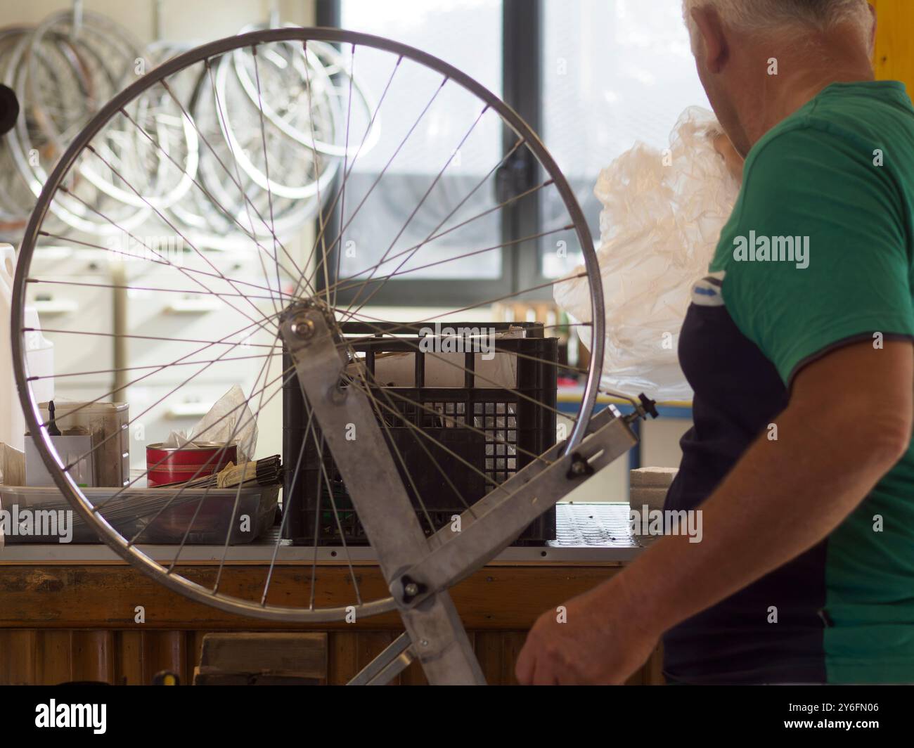 Senior mechanic mounts a tire on a wheel in a small bicycle repair shop ...