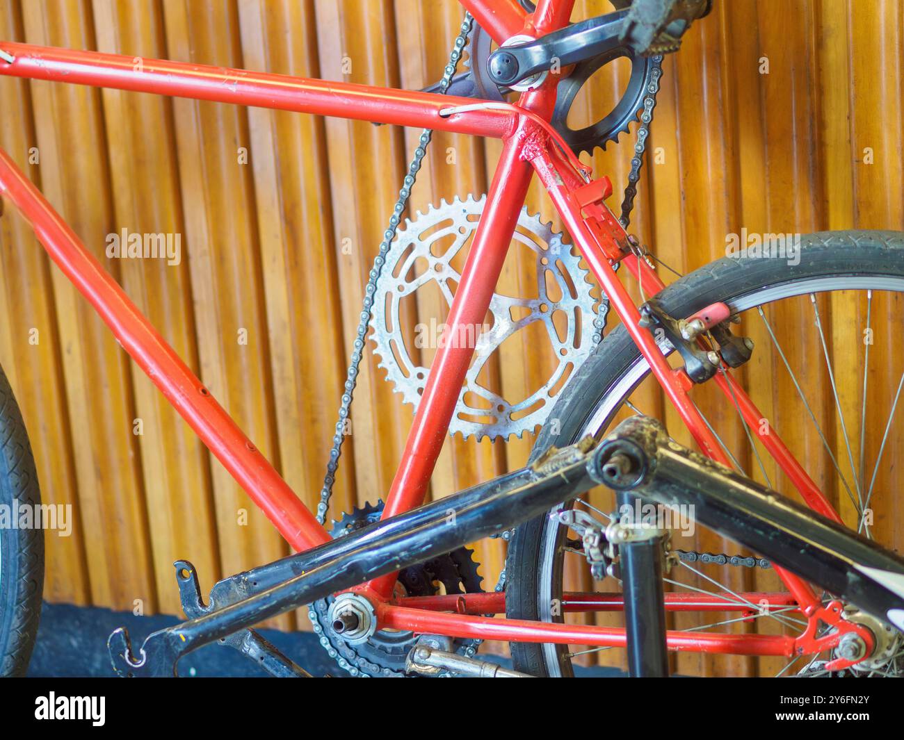 Red bicycle leans against a wooden wall, showcasing its gears and chain ...