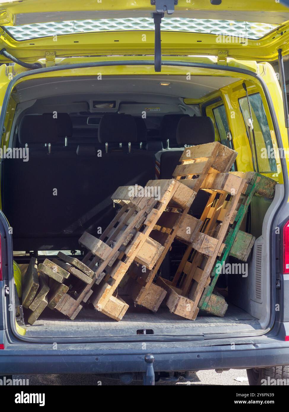 Yellow delivery van is parked with its back open, revealing a stack of ...