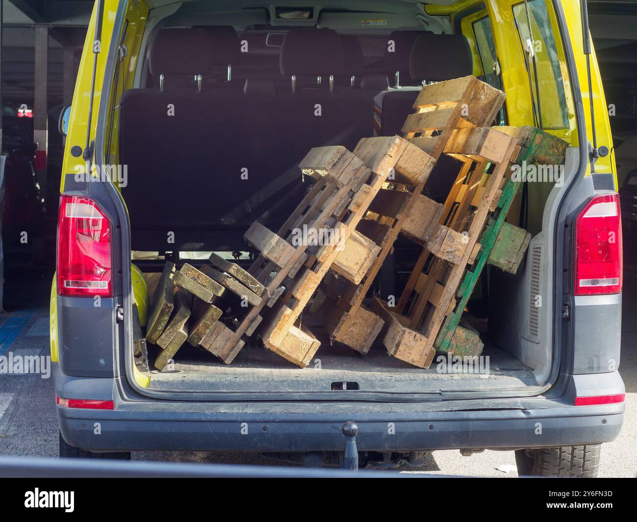 Yellow delivery van is parked with its back open, revealing a stack of ...