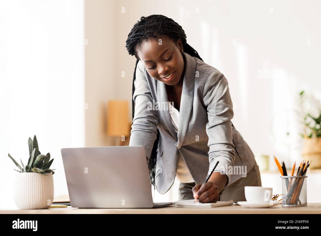 Busy black secretary taking notes while standing up near her desk Stock ...