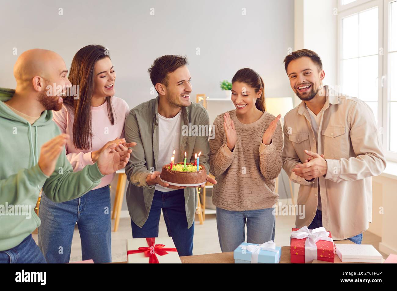 Happy man holding cake standing with friends congratulating him with a ...
