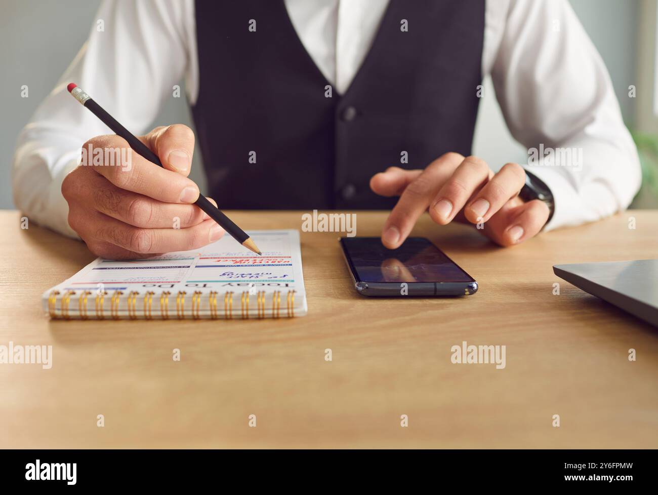 Man planning to do list in notepad sitting at the desk with smartphone ...