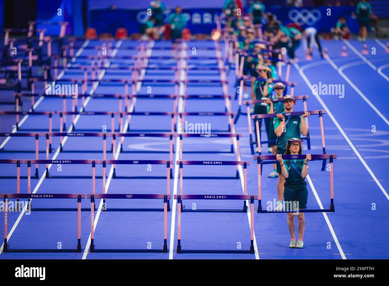 Athletics volunteer moving the hurdles in a synchronized manner at the ...