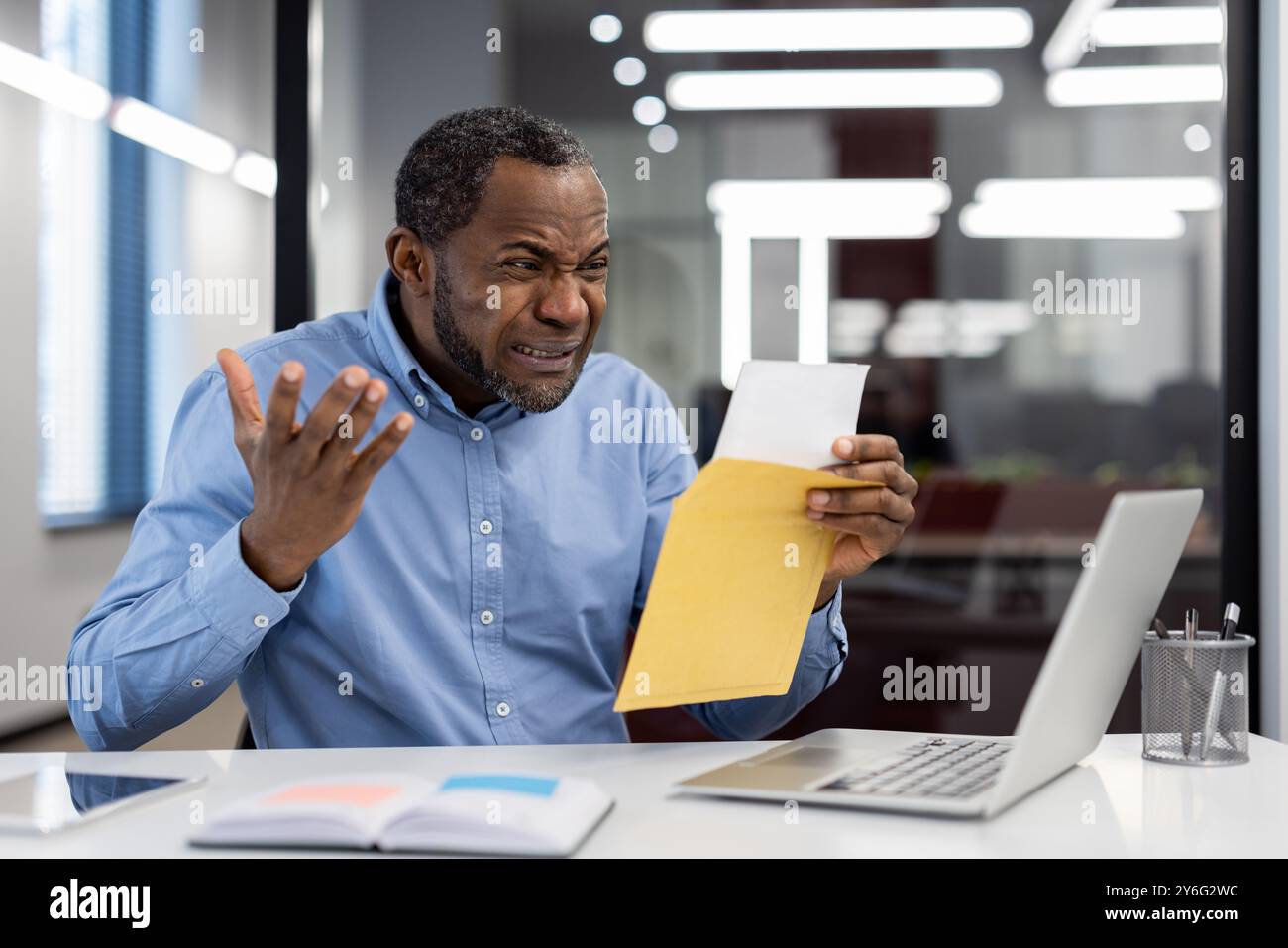 Businessman seated at desk in modern office, reading letter with ...