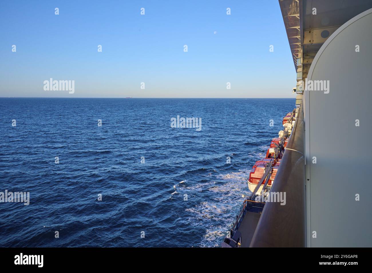 A large ship sails calmly on the blue ocean under a clear sky, with a ...