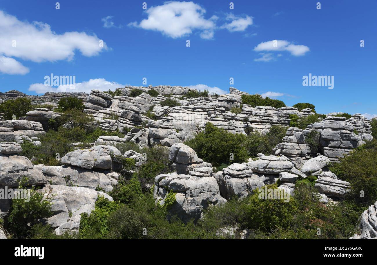 Barren rock formations under a bright blue sky with white clouds and ...