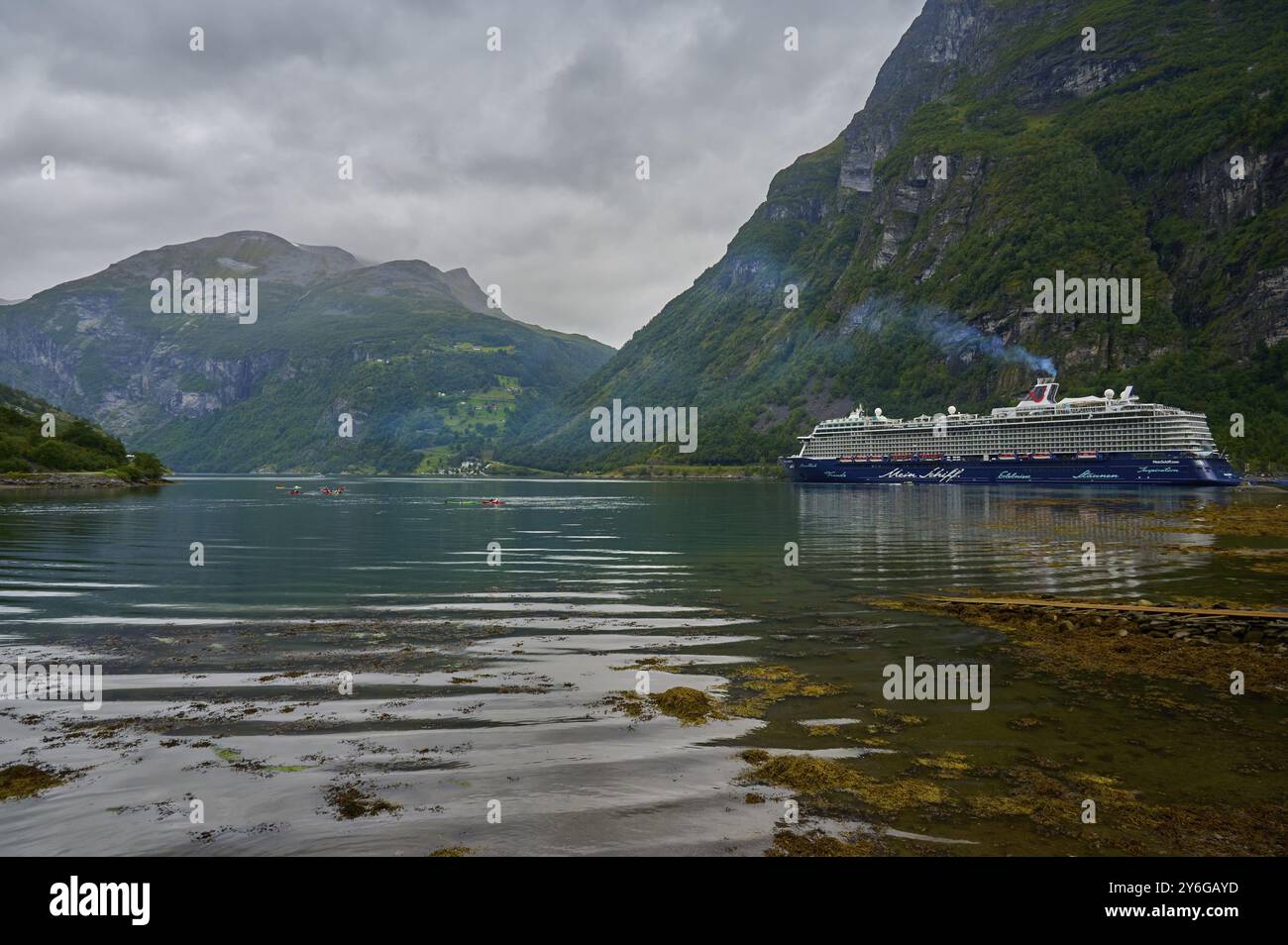 A large cruise ship, Mein Schiff 6, lies in the fjord, surrounded by ...