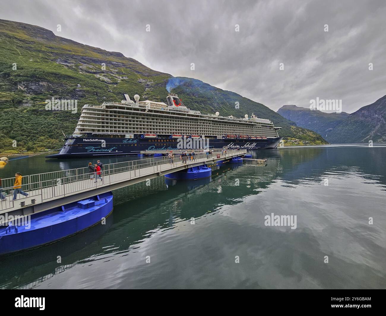 A large cruise ship, Mein Schiff 6, lies in the fjord, surrounded by ...