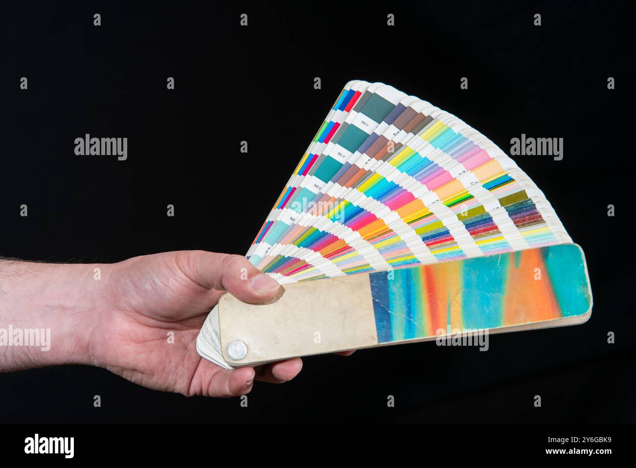 Close-up of hand holding a fanned out color guide against black ...