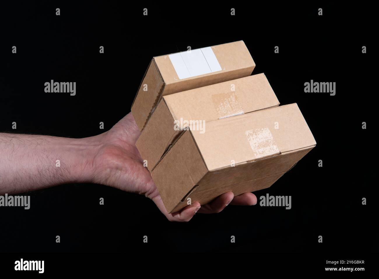 Close-up of man's hand holding three small corrugated cardboard boxes ...