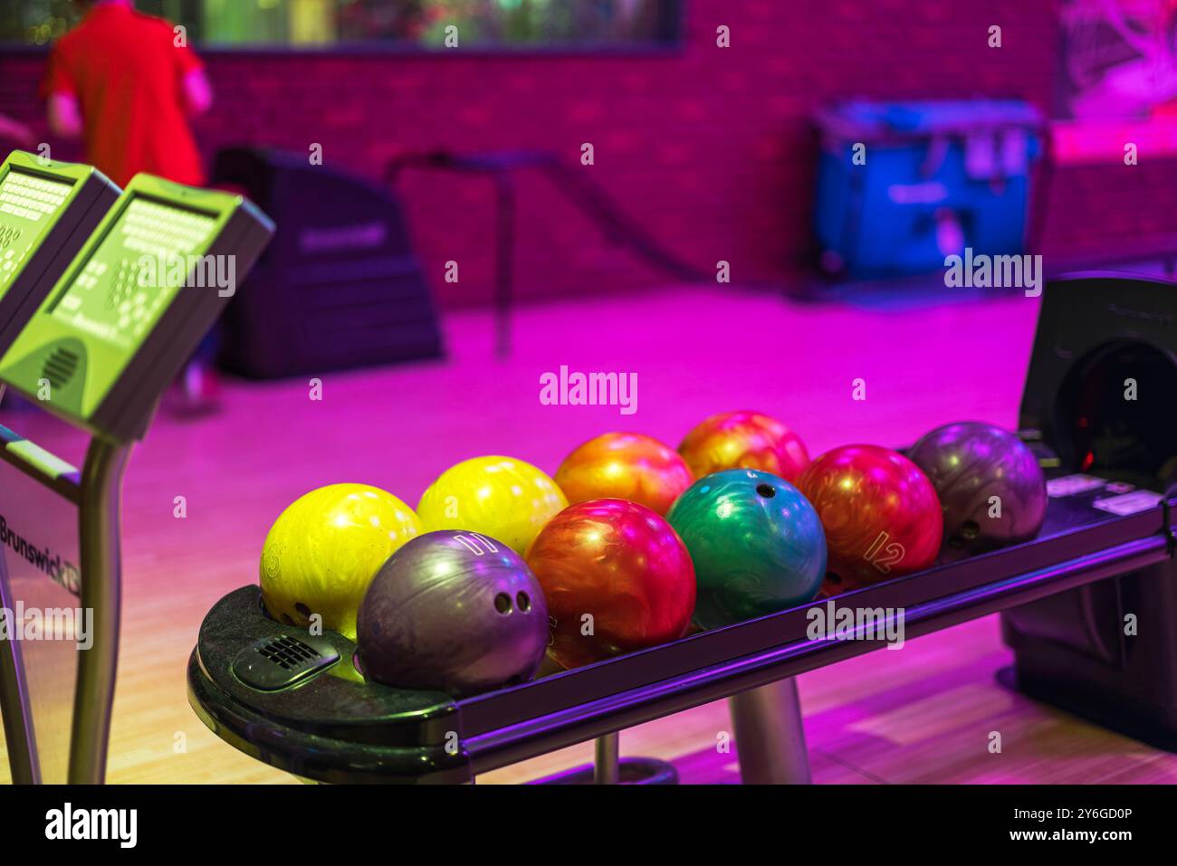 Colorful bowling balls on rack at ball return system in bowling alley ...