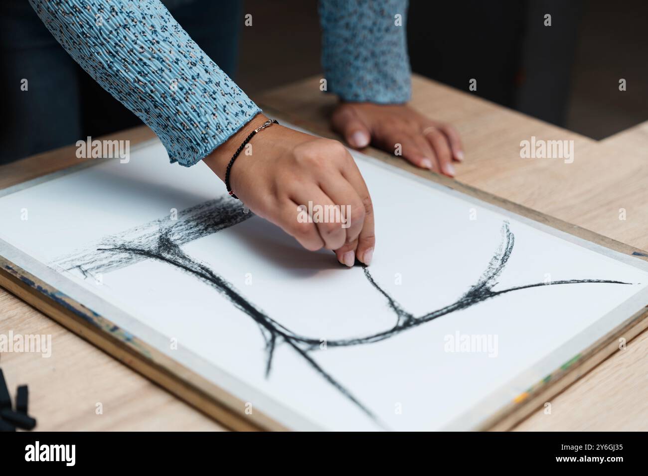 Person sketching abstract lines on paper with charcoal in a creative ...