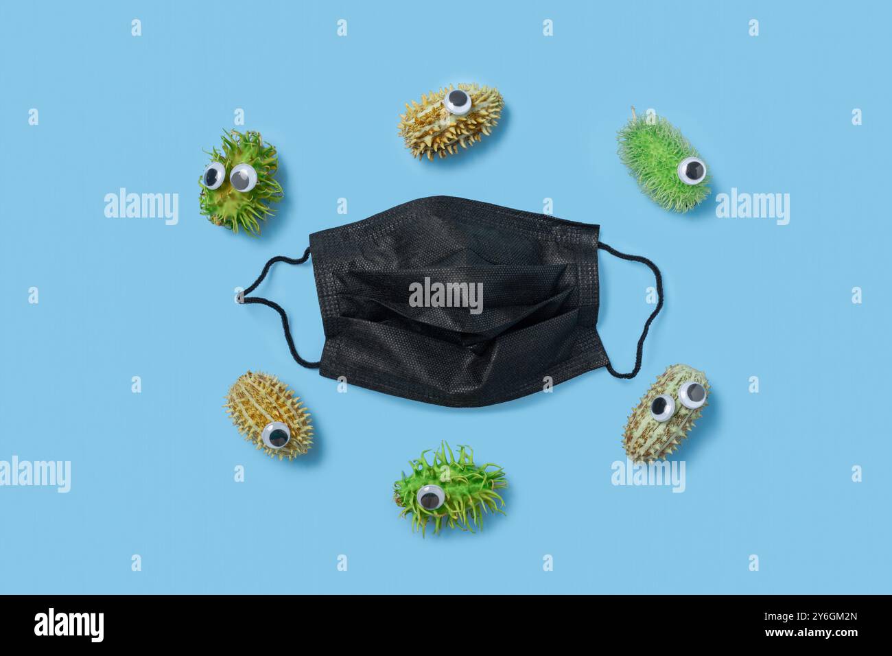 Black face mask surrounded by cartoon bacteria on a blue background ...